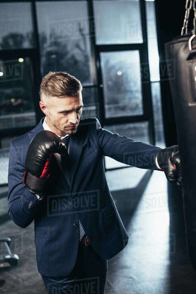 Handsome businessman in suit boxing in gym - Stock Photo - Dissolve