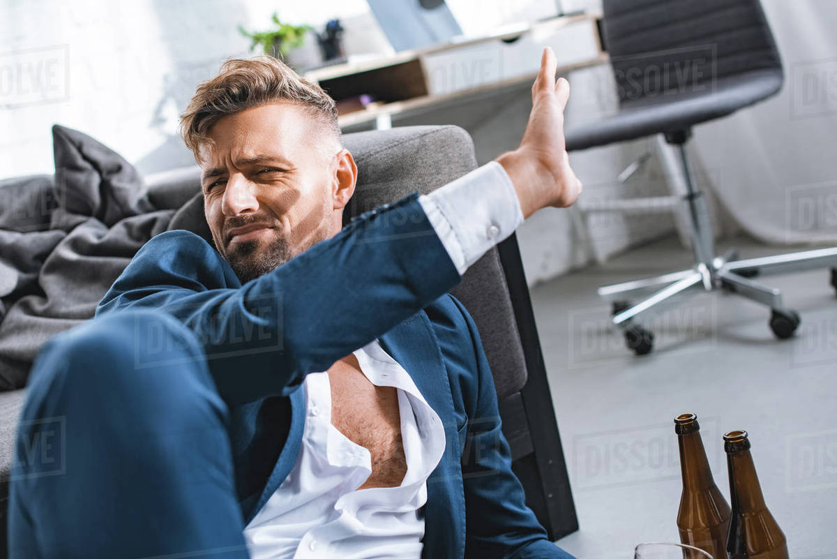 Drunk businessman putting hand against sunshine in living room ...