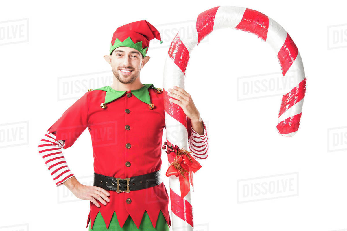 smiling man in christmas elf costume with hand on hips standing near ...