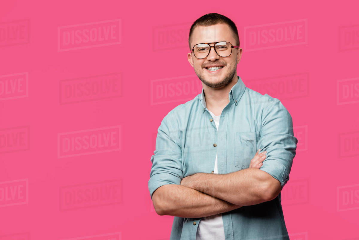 handsome happy man standing with crossed arms and smiling at camera ...