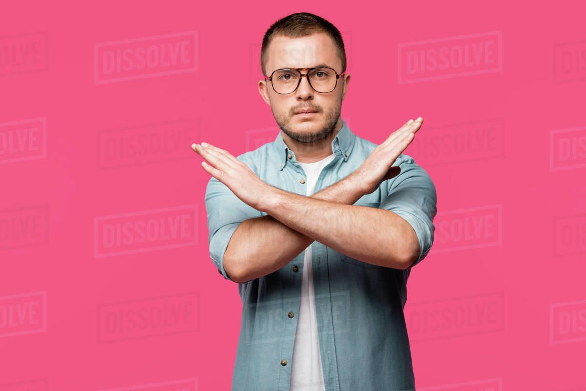 young man gesturing no with crossed arms and looking at camera isolated ...