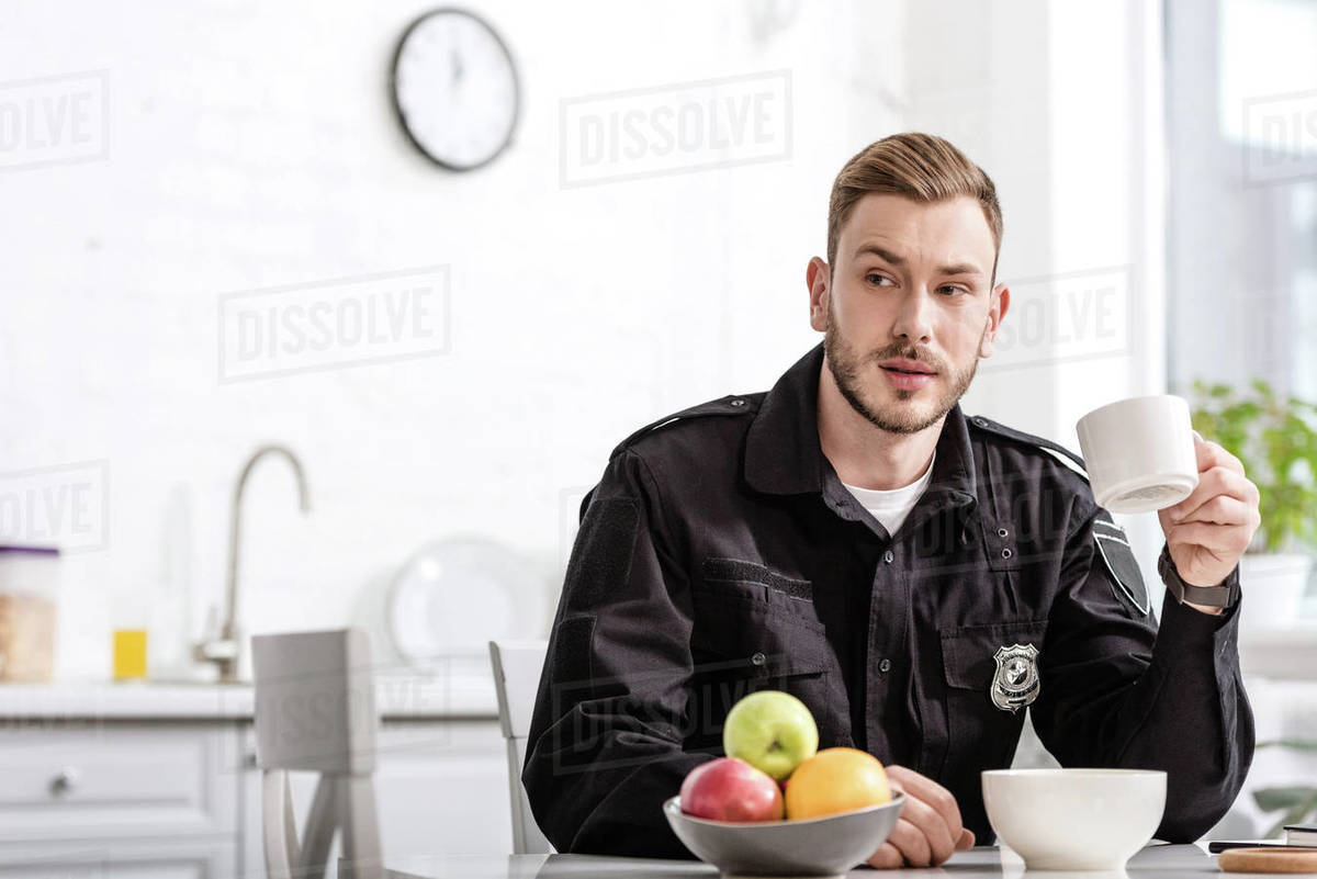 handsome policeman at kitchen sitting, holding cup of hot coffee and ...