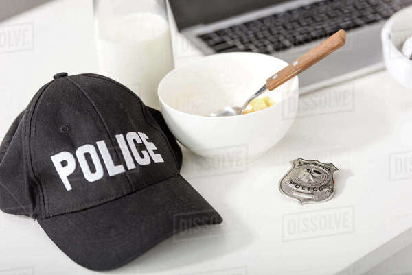 police cap, bowl with cornflakes, police badge and laptop on table ...