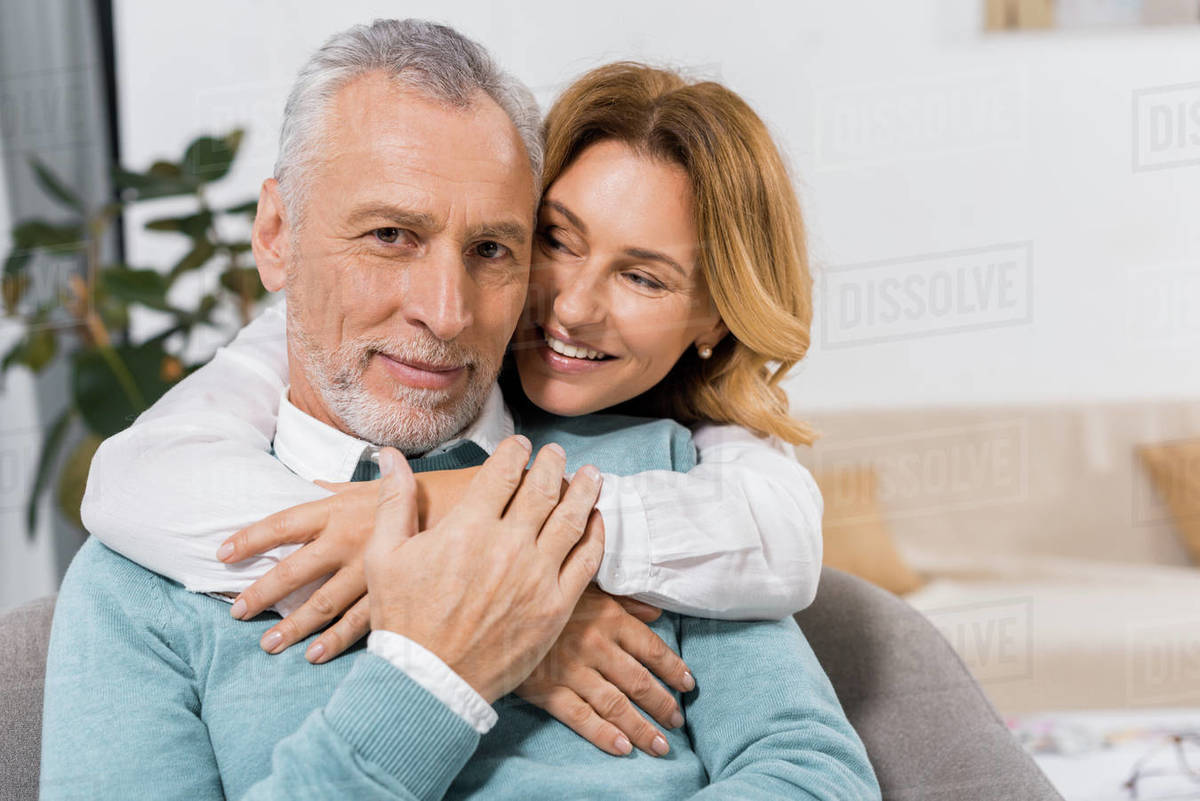 Selective focus of happy attractive woman embracing middle aged husband ...