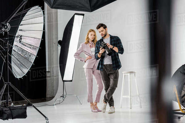 Young photographer and model checking photos on camera in studio ...