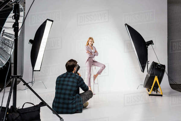 Back view of young photographer shooting beautiful female model in ...