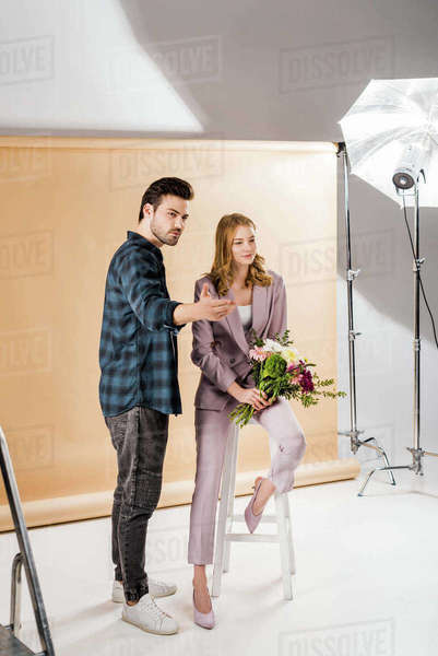 Young photographer talking with beautiful female model in photo studio ...