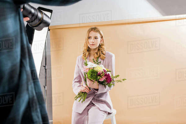 Cropped shot of photographer shooting young female model with flowers ...