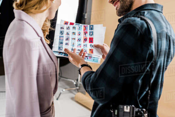 Cropped shot of photographer and model looking at photos in studio ...