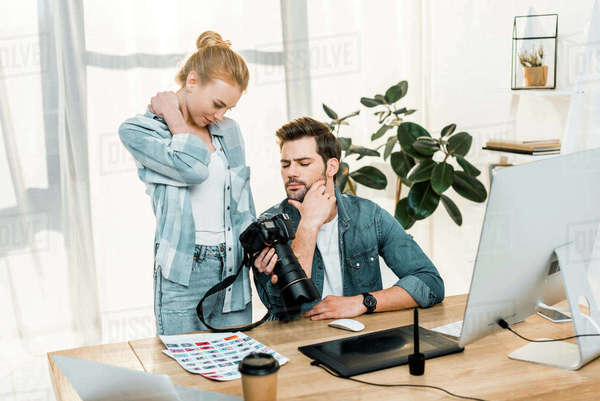 Professional young photographers using photo camera while working ...