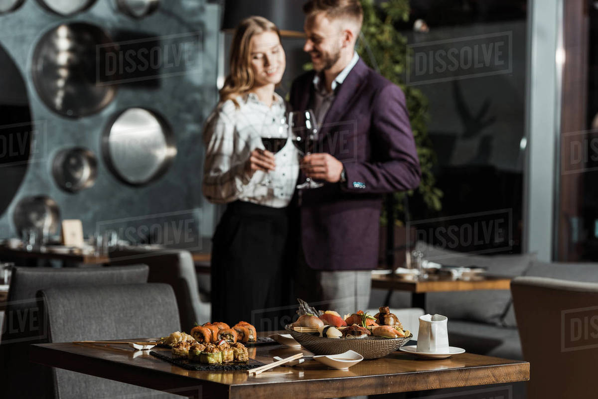 Cropped view of attractive couple near the table served with sushi in ...