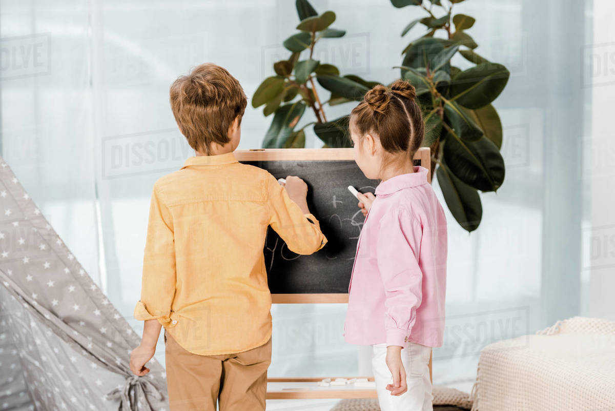 Back view of children writing on chalkboard together - Royalty-free ...
