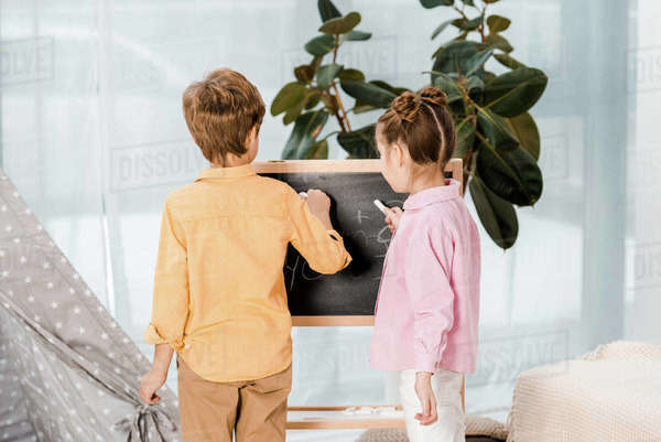 Back view of children writing on chalkboard together - Royalty-free ...