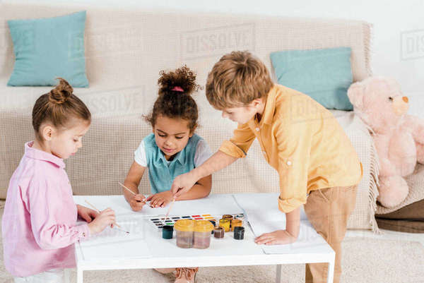 High angle view of adorable multiethnic children drawing with paints ...