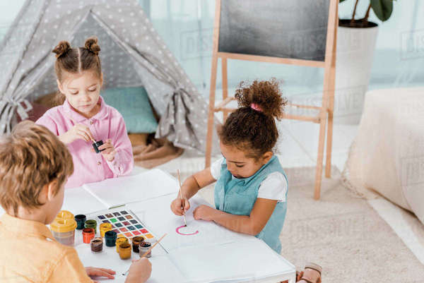 High angle view of adorable little multiethnic kids drawing together ...