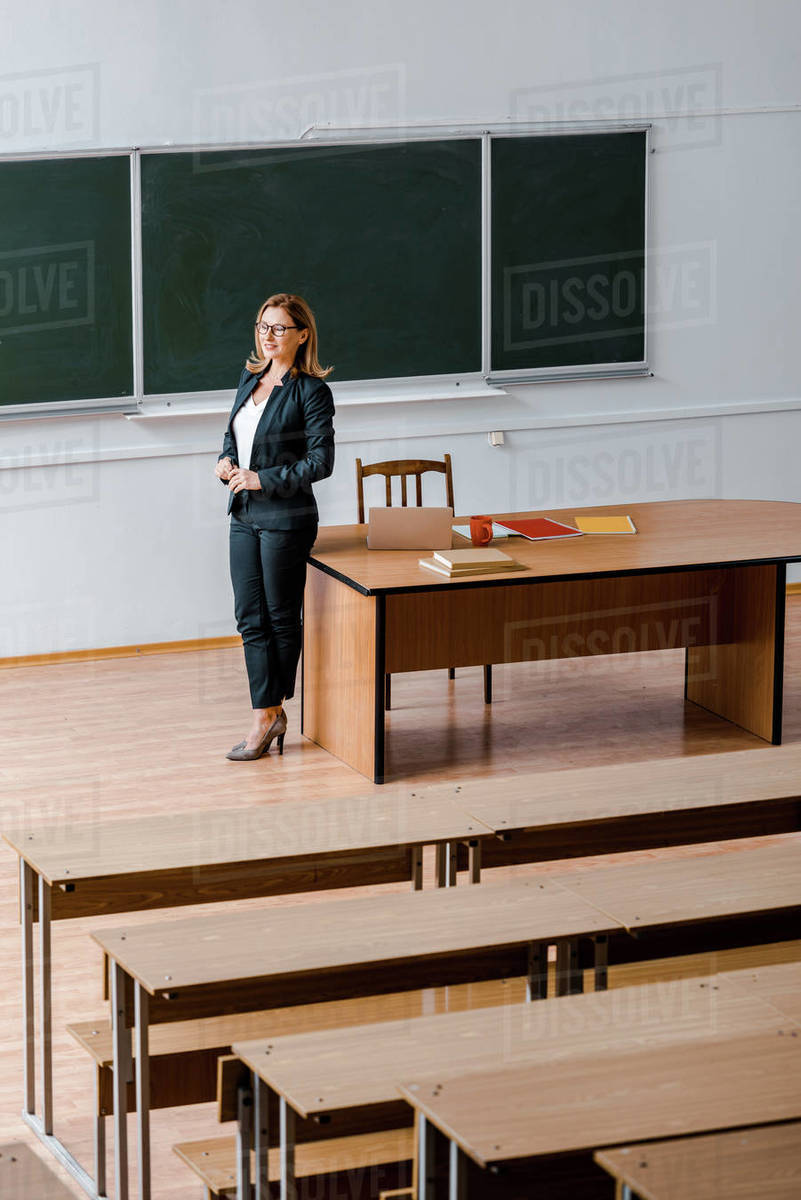 Female university professor in formal wear standing near chalkboard in ...