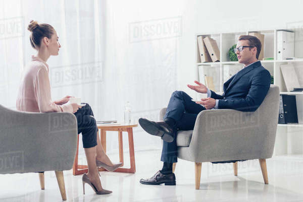 Side view of handsome businessman giving interview to journalist in ...