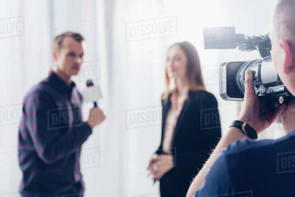 Selective focus of businesswoman in suit giving interview to journalist ...