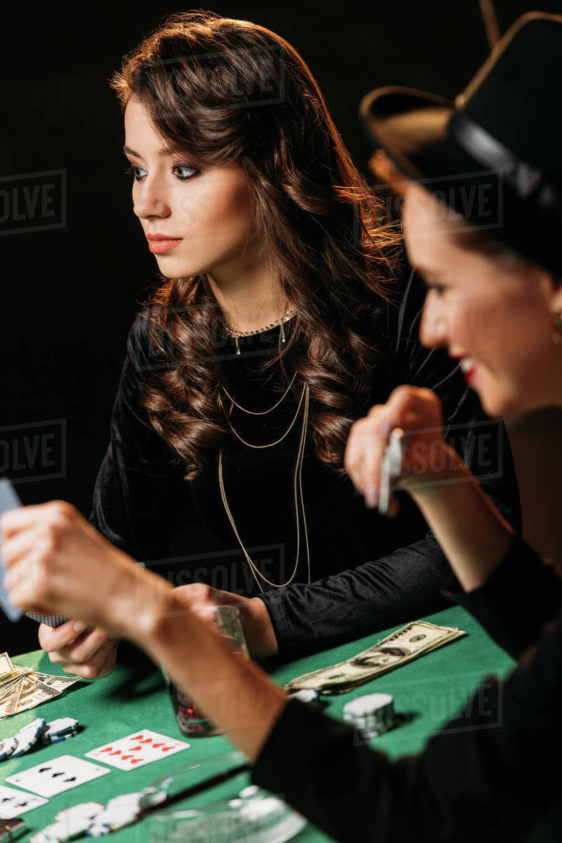 Beautiful women playing poker with cards and chips at table in casino ...