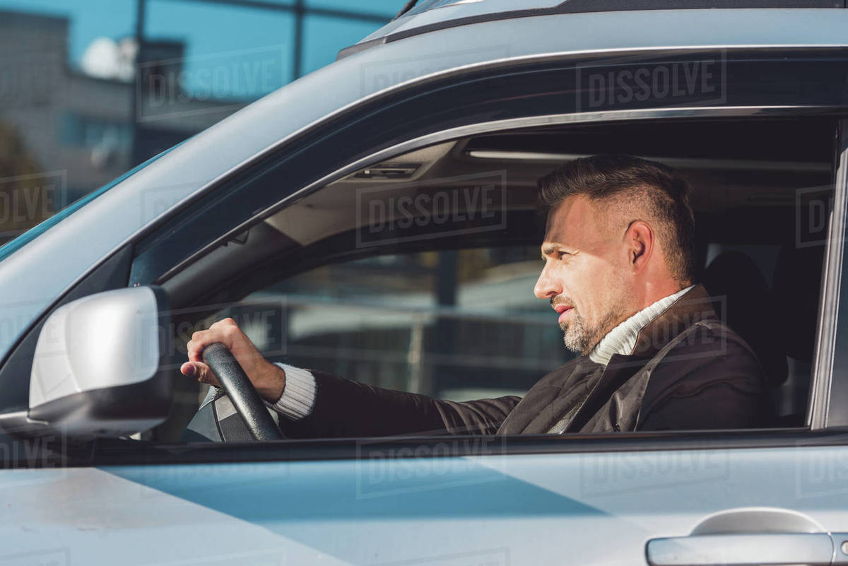 Handsome driver sitting in car and holding steer - Royalty-free Stock ...