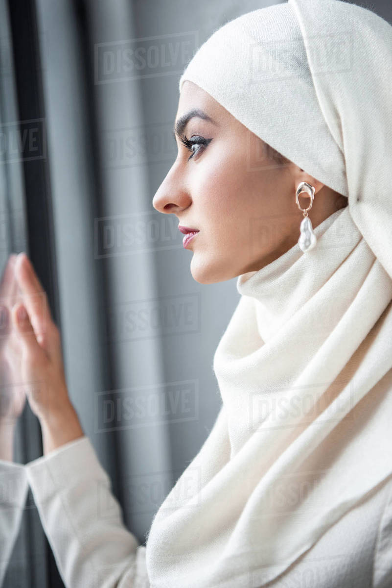 Side view of beautiful young muslim woman looking at window - Royalty ...