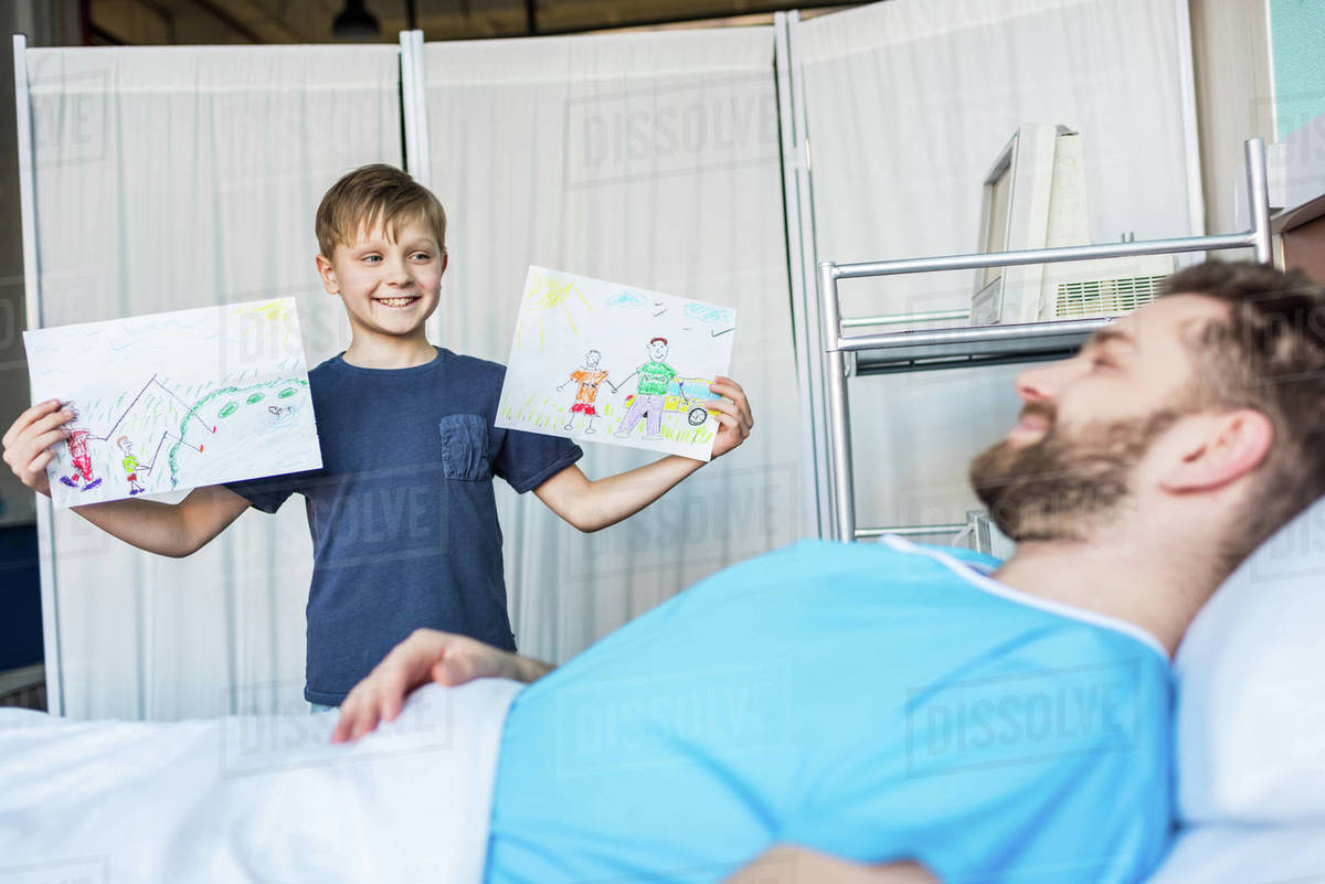 Little son showing sick father his drawings at ward, dad and son ...
