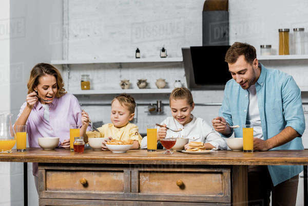 Happy family eating porridge at table in kitchen - Royalty-free Stock ...