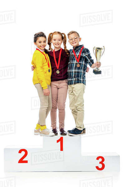Happy kids with medals and trophy cup smiling and standing on winner ...