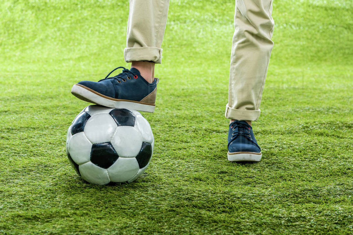 Cropped view of boy with leg standing on soccer ball on lawn - Royalty ...