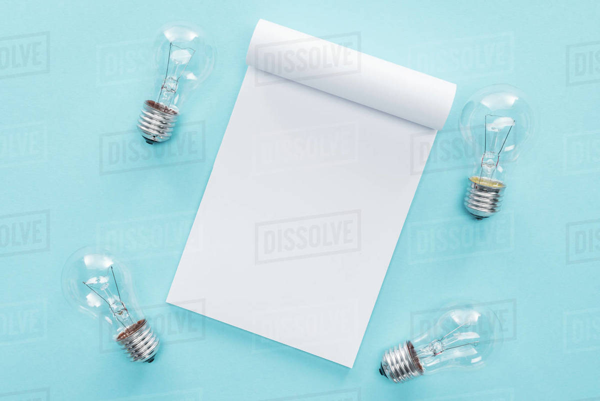 Top view of blank notebook with light bulbs on blue background, having ...