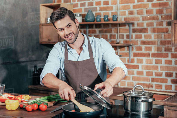 Happy handsome man with apron cooking - Stock Photo - Dissolve