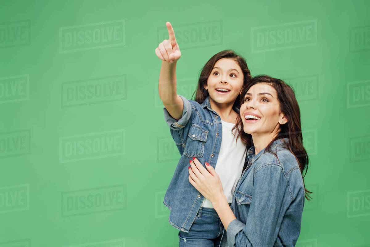 Excited daughter pointing with finger while happy mother looking up ...