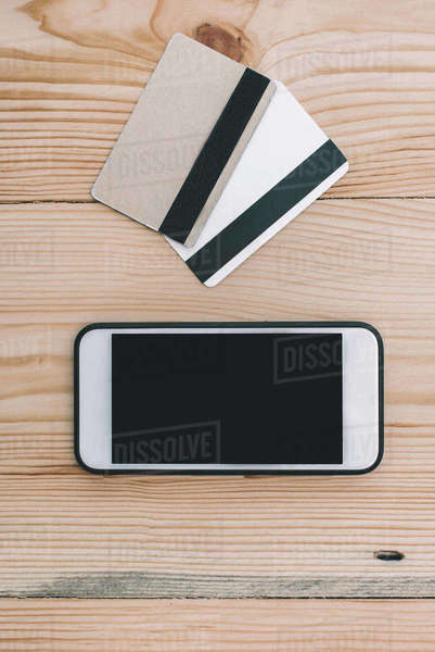 Top view of smartphone with blank screen and credit cards on wooden ...