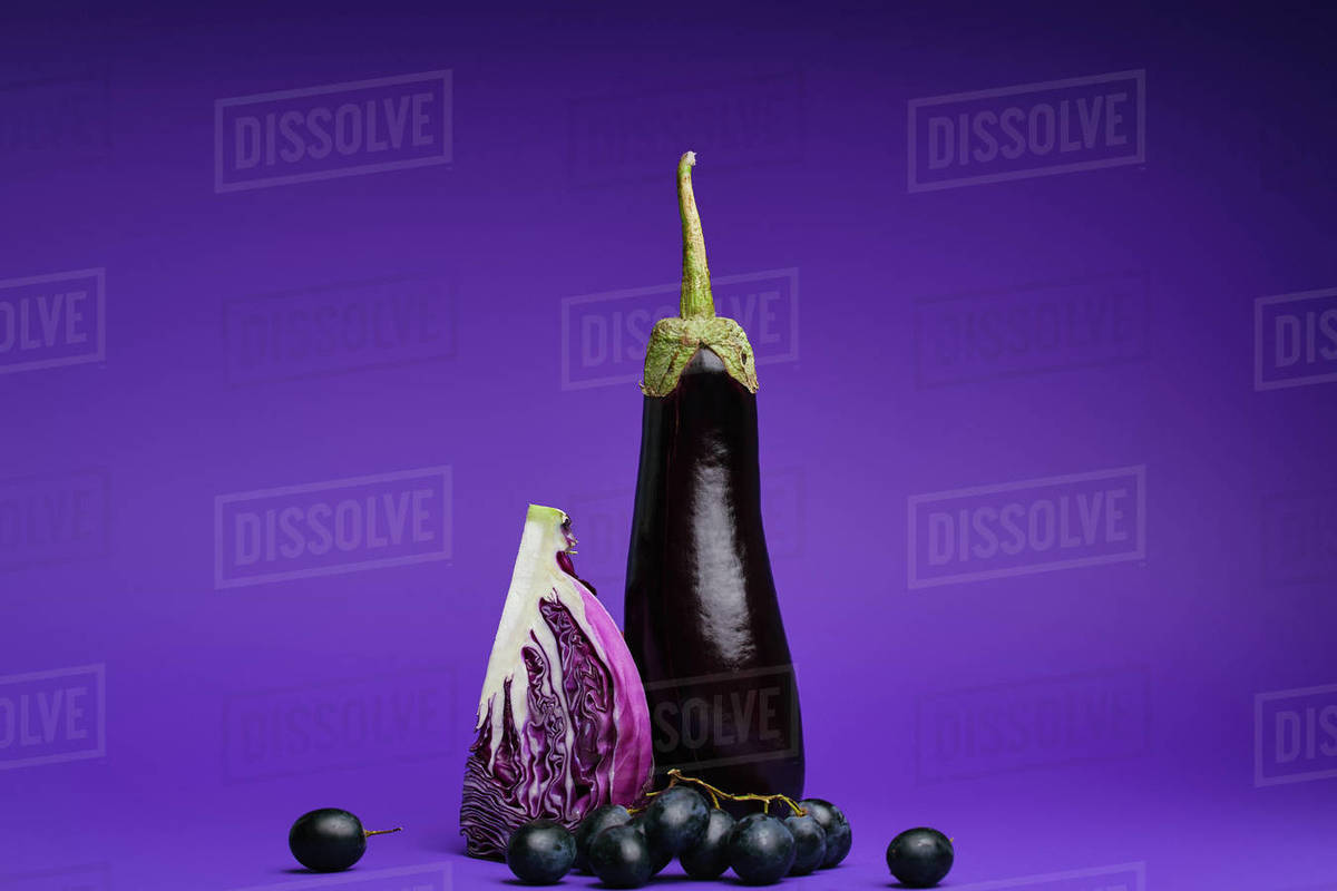 Close-up view of sliced cabbage, grapes and eggplant on purple ...