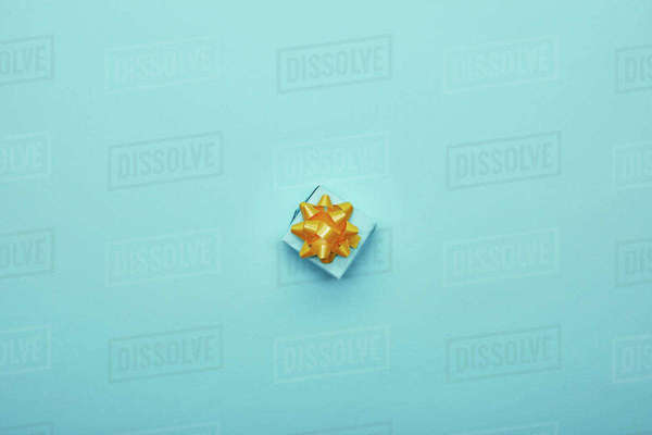Top view of bright gift box with golden bow on blue background - Stock ...
