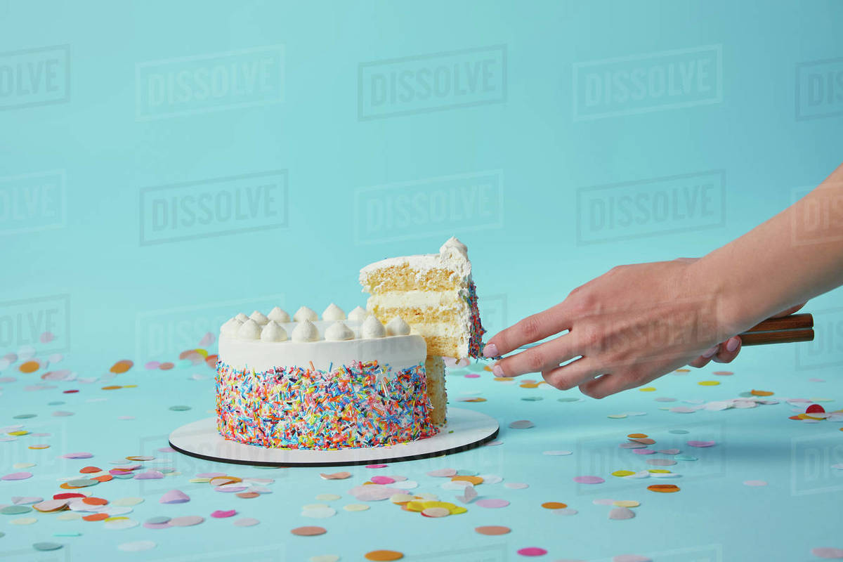Partial view of woman taking piece of delicious cake on blue background ...