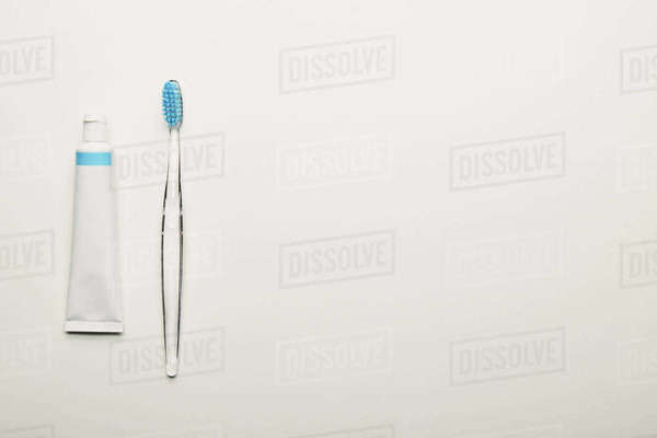 Top view of toothbrush and toothpaste arranged on white backdrop ...