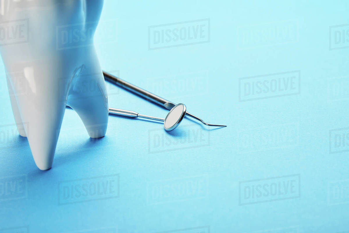 Close up view of sterile dental mirror, probe and tooth model arranged ...