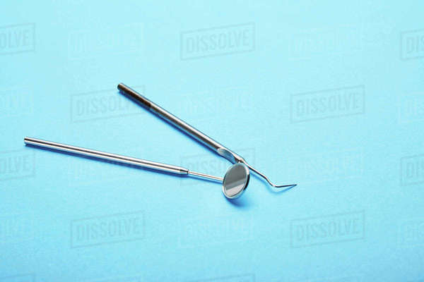 Close up view of dental mouth mirror and probe on blue surface ...
