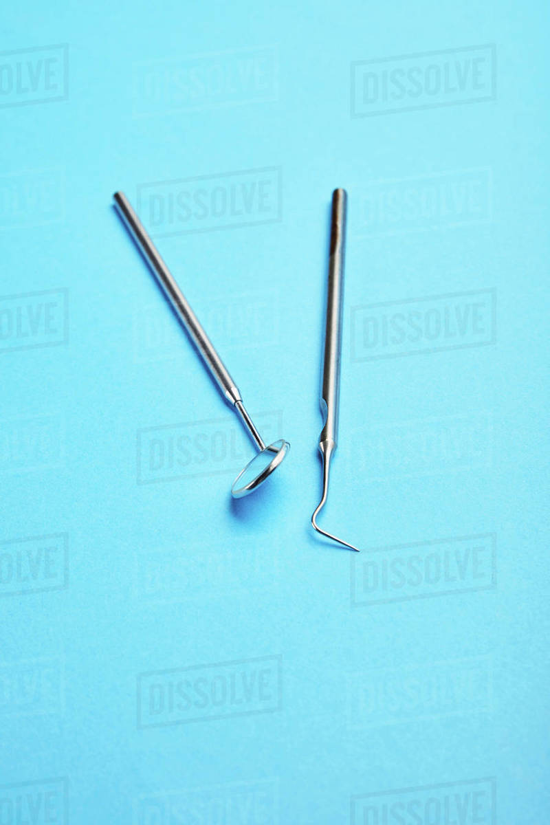 Close up view of dental mouth mirror and probe on blue surface ...