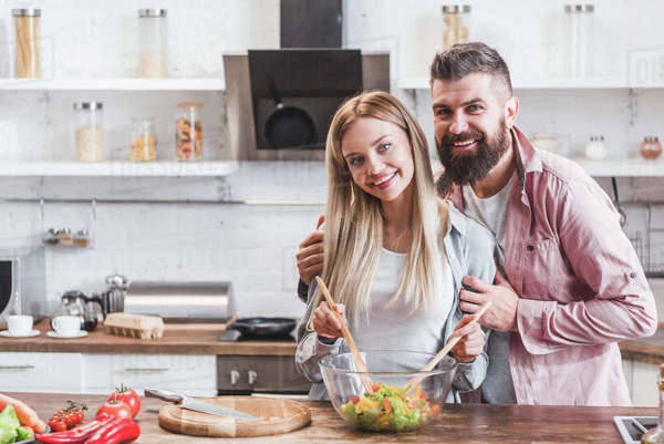 Smiling couple hugging while cooking dinner at kitchen - Royalty-free ...