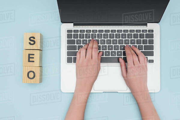 Top view of female seo manager typing on laptop keyboard on light blue ...