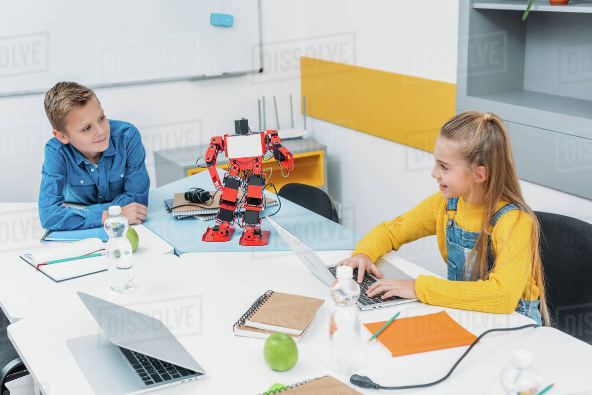 Schoolchildren programming robot together and using laptops during stem ...