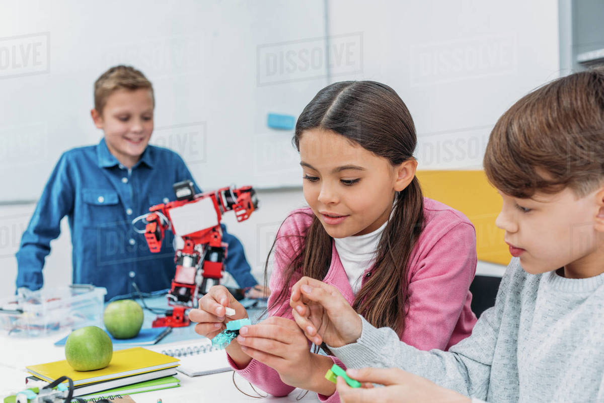 Happy classmates making a robot during stem robotics lesson - Royalty ...