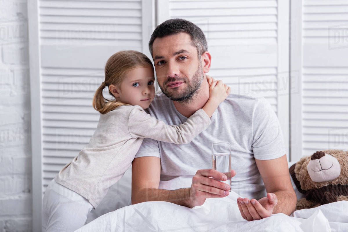 Adorable daughter hugging sick father in bedroom - Royalty-free Stock ...