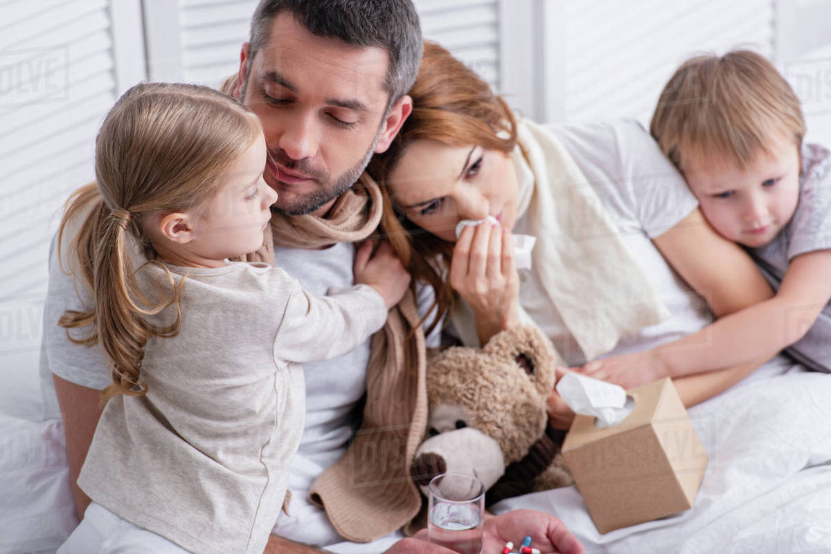 Adorable sister and brother hugging sick parents in bedroom - Royalty ...