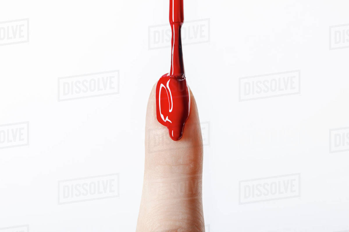Cropped view of woman applying dripping red nail polish on fingernail ...