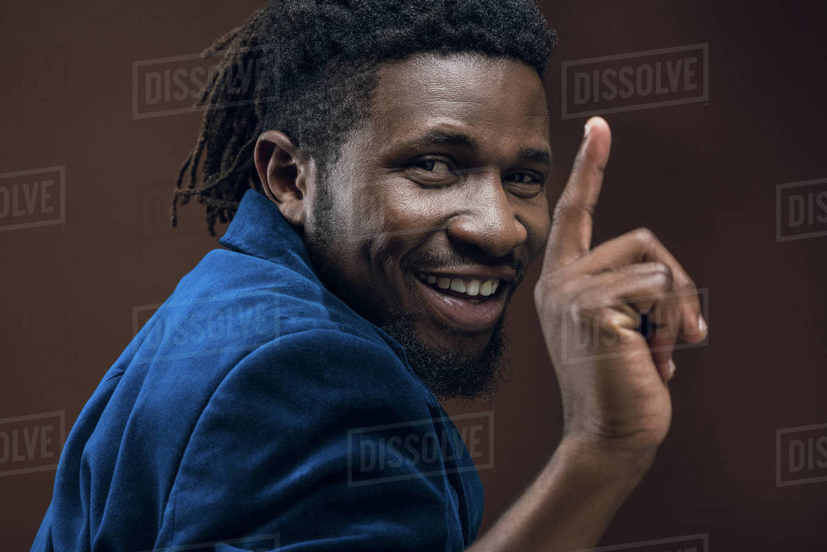 Smiling African American man showing one finger up isolated on brown ...
