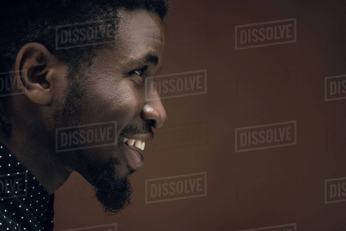 Side view of smiling African American man isolated on brown - Royalty ...