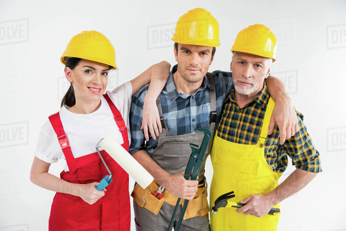 Professional construction workers holding tools and looking at camera ...